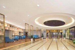Um saguão de hotel com design circular no teto, área de estar e balcão de recepção.