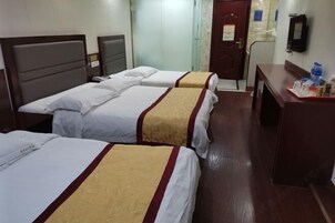 Quarto de hotel com três camas, uma mesa e uma porta.