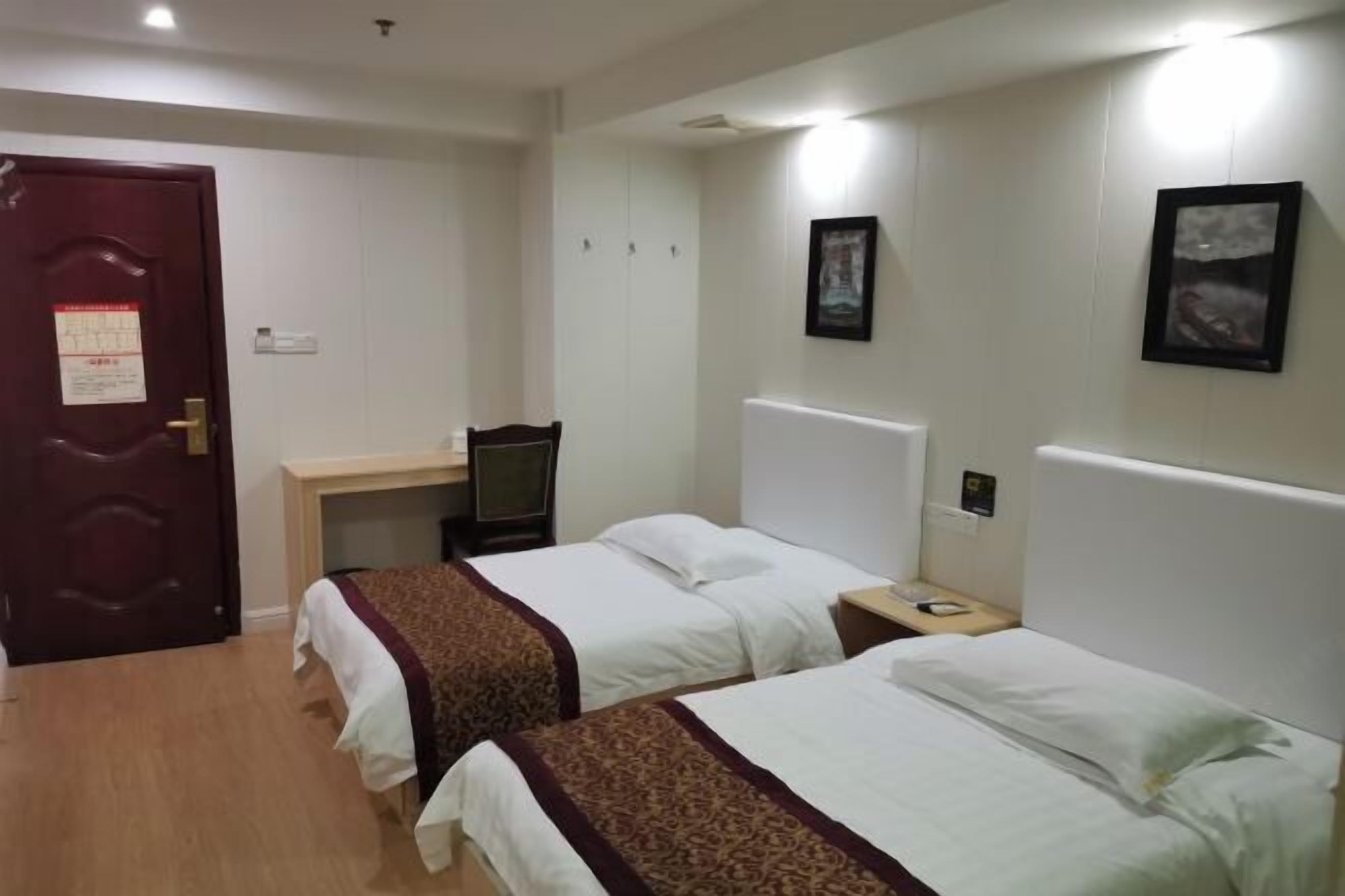 Quarto de hotel com duas camas, uma escrivaninha e uma cadeira.