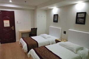 Quarto de hotel com duas camas, uma escrivaninha e uma cadeira.
