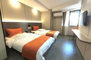 Quarto de hotel com duas camas, uma escrivaninha e uma televisão.
