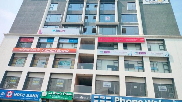 Um edifício com vários andares e diversos estabelecimentos comerciais, incluindo SBI Life, ICICI Bank, HDFC Bank, La Pino's Pizza e PhoneWale.