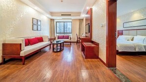 Quarto de hotel com sofá, mesa pequena, cama e televisão.