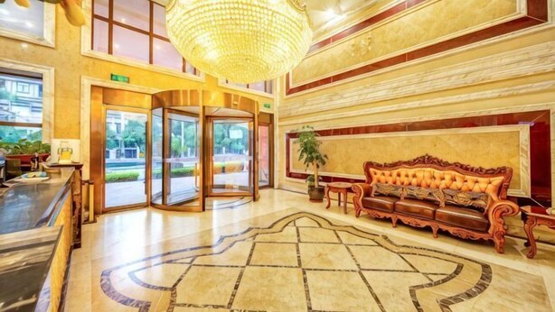 Um hall com um lustre imponente, uma porta giratória, um sofá confortável e um piso estampado.