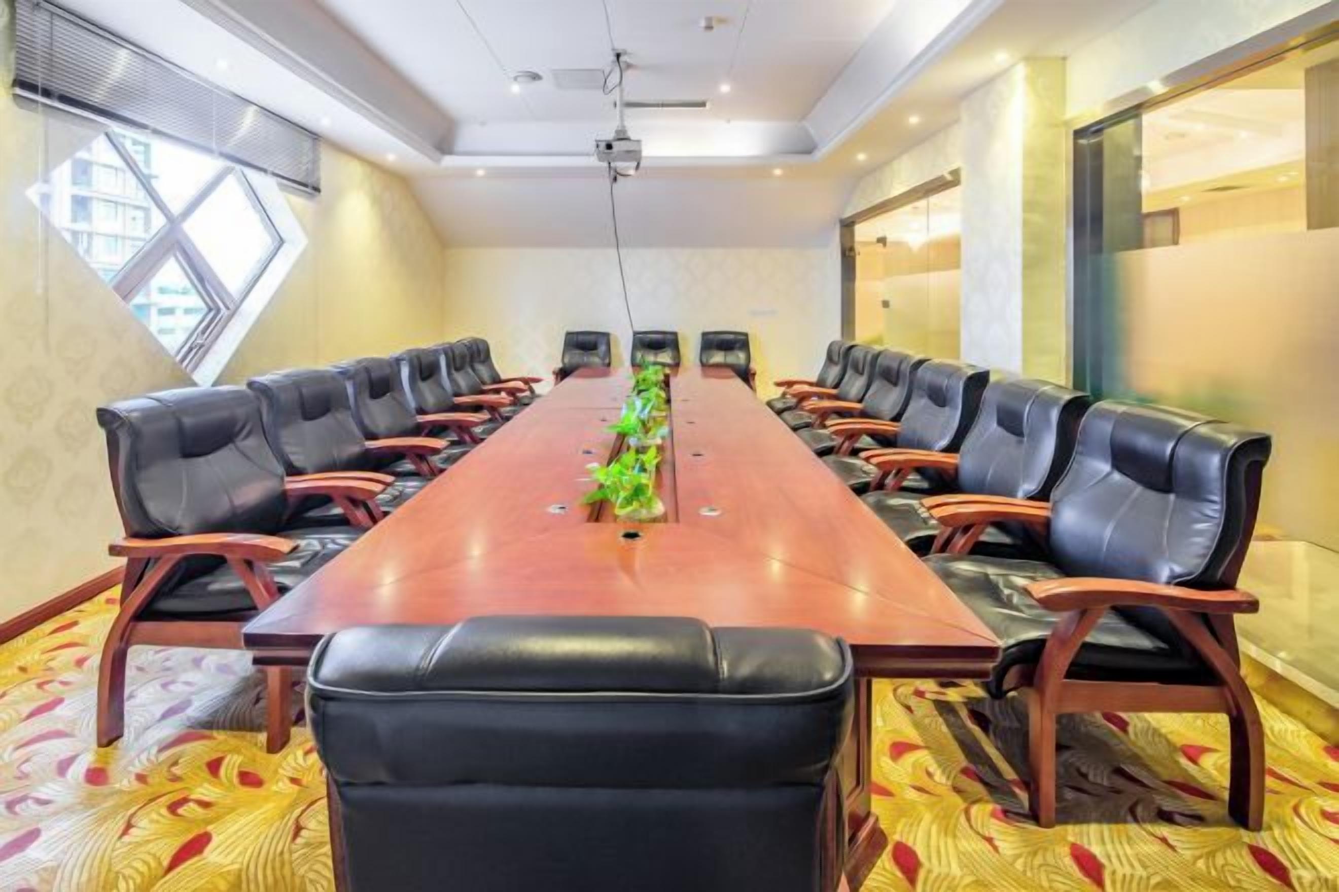 Uma sala de conferências com uma mesa comprida, várias cadeiras e um projetor.