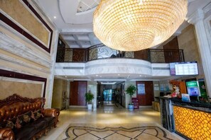 Um saguão de hotel com um lustre imponente, uma recepção e uma área de estar.