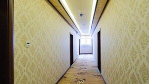 Um corredor estreito com papel de parede estampado e piso de madeira com motivos florais.