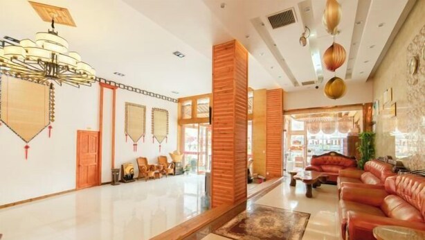Um hall de hotel com um lustre moderno, detalhes em madeira, assentos de couro e piso polido.