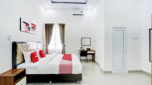 Quarto de hotel moderno com uma cama bem arrumada, uma escrivaninha e uma porta.