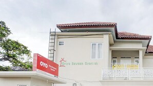 Um edifício de dois andares com varanda e placa indicando ser uma pensão.