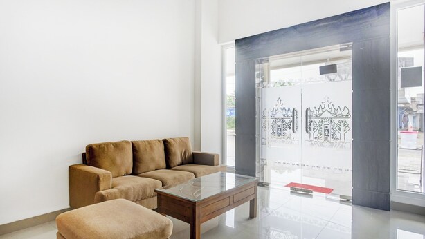 Uma sala de estar moderna com sofá, banquinho e mesa de centro de vidro.