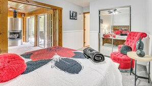 Quarto com uma cama grande, uma cadeira vermelha, uma mesa pequena e um espelho.