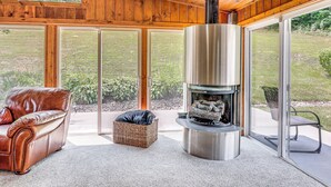 Um quarto aconchegante com sofá de couro, lareira e grandes janelas com vista para o exterior.