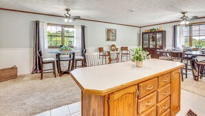 Uma cozinha espaçosa com uma ilha grande, armários de madeira e uma área de jantar com cadeiras e mesas.