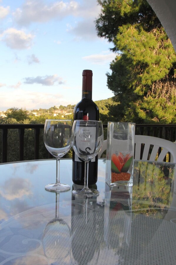 Uma mesa com uma garrafa de vinho, duas taças de vinho e um copo decorativo com uma planta.