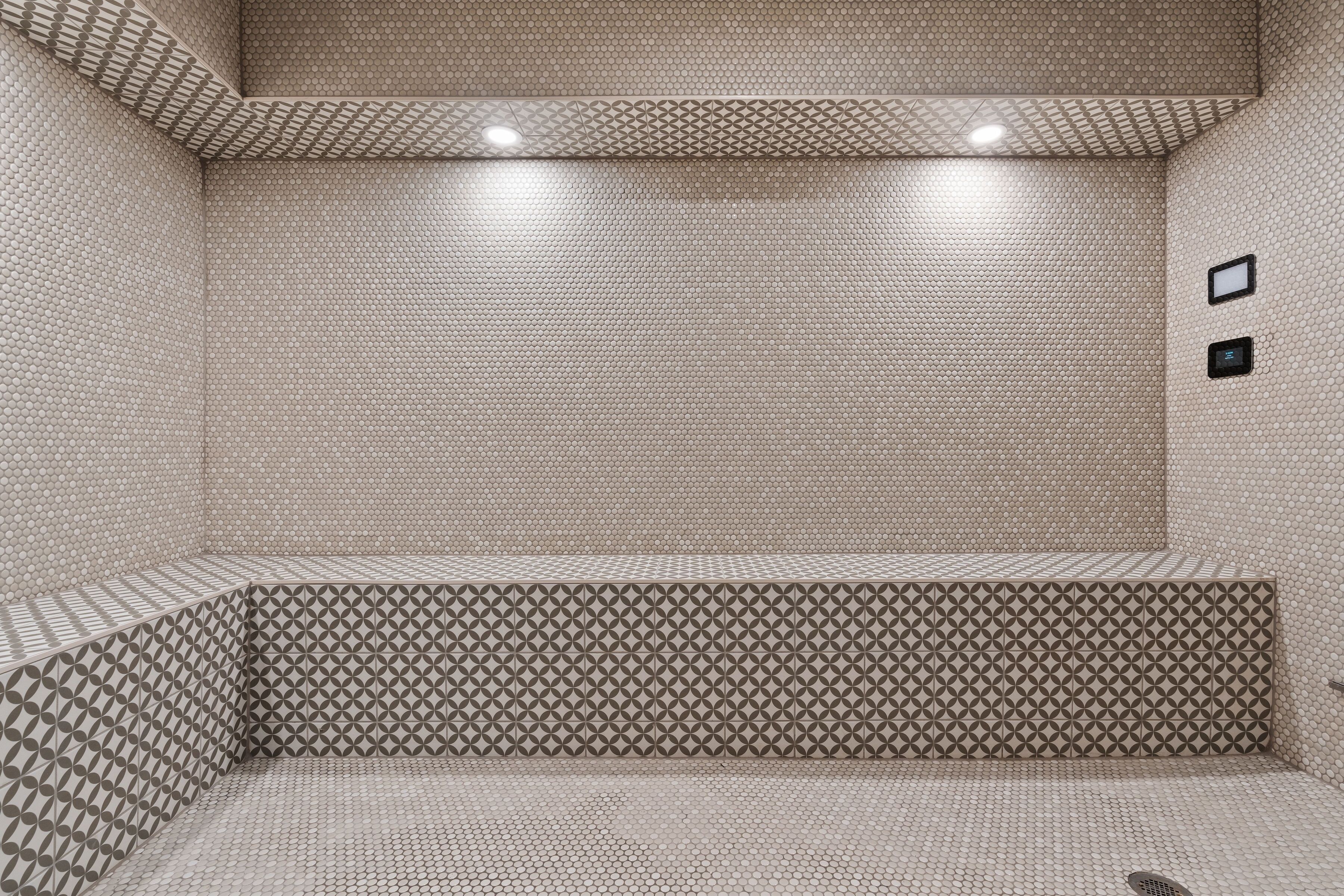 Um chuveiro revestido com azulejos e um padrão geométrico, com iluminação embutida.