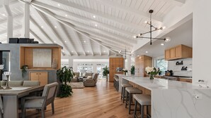 Uma cozinha espaçosa com ilha de mármore, armários de madeira e uma luminária pendente moderna.