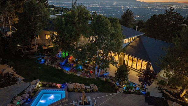 Um imóvel residencial com piscina, área de estar externa e vista para a paisagem urbana ao entardecer.