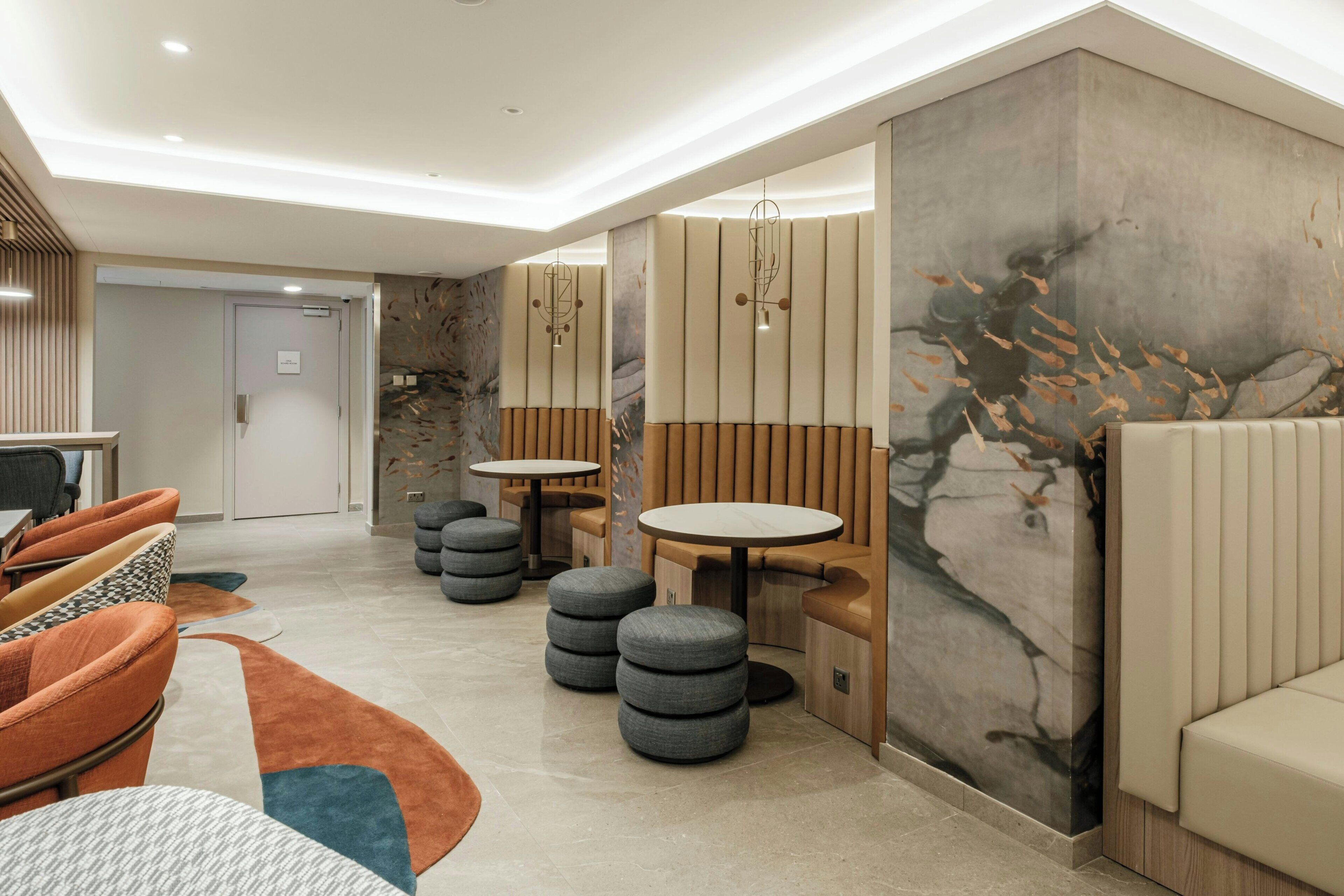 Decoração moderna com áreas de estar, balcão de recepção e um grande mural abstrato.