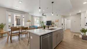 Uma cozinha espaçosa com uma ilha central, cadeiras de madeira, uma mesa de jantar e um ventilador de teto.
