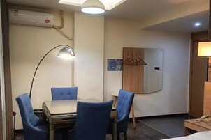 Quarto de hotel com cama, escrivaninha, cadeira, mesa e espelho.