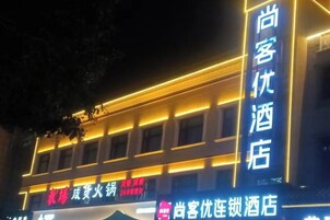 Um hotel com letreiros iluminados, uma placa vertical destacada e um banner com texto.