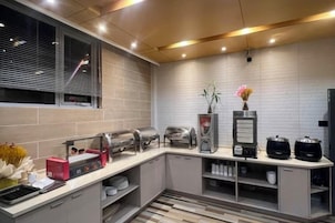 Cozinha moderna com espaço para café, pia e janela com persianas.