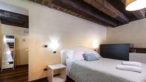Quarto com cama, mesa de cabeceira e ventoinha no teto.