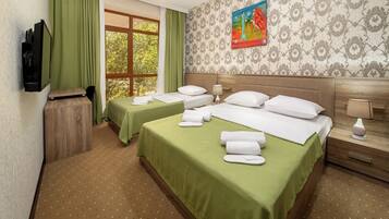 Quarto de hotel com duas camas, televisão, secretária e janela com cortinas.