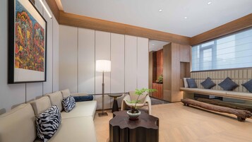 Uma sala de estar moderna com um sofá, uma mesa de centro com uma planta e um banco com almofadas.