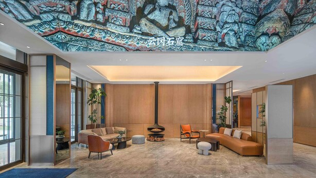 Um hall moderno com um grande mural, assentos confortáveis e uma lareira central.