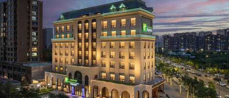 Um hotel Holiday Inn Express de vários andares com design moderno, com entrada destacada e terraço no telhado.
