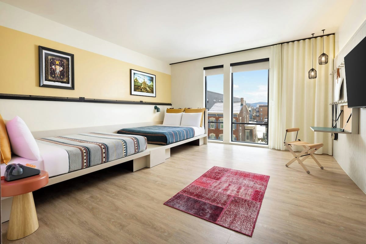 Quarto de hotel moderno com uma cama, uma escrivaninha e vista para a cidade.