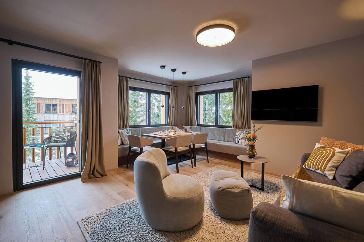 Uma sala de estar moderna com sofá, pufê e área de jantar com mesa e cadeiras.