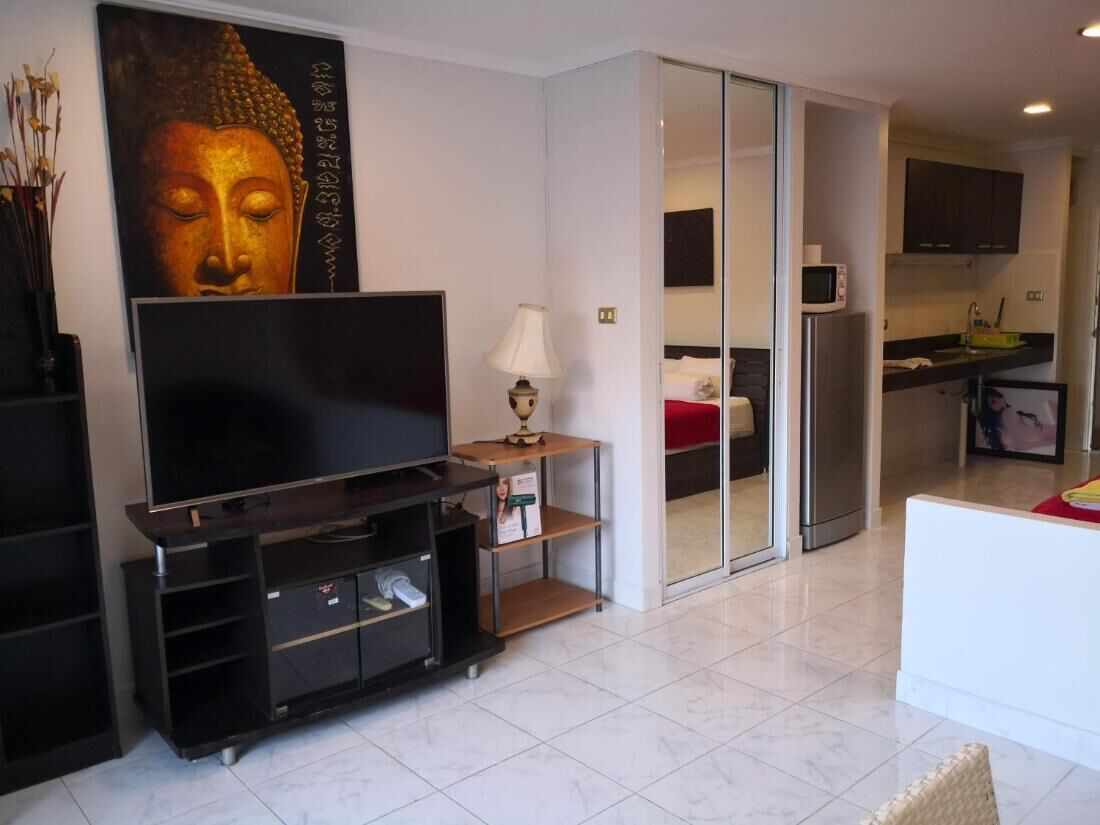 Uma sala de estar moderna com televisão de tela plana, uma luminária e uma estátua de Buda na parede.