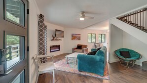 Uma sala de estar ampla com um sofá branco, poltrona verde-água e um tapete estampado.