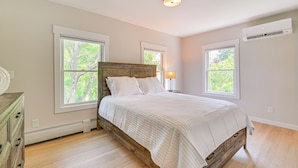 Quarto com cama de madeira, janelas amplas e ar condicionado.