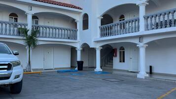 Um hotel com um pátio central, fachada branca e várias varandas.