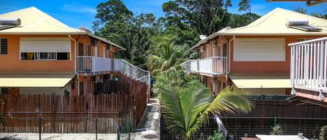 Uma área residencial com duas casas, uma cerca de madeira e uma palmeira.