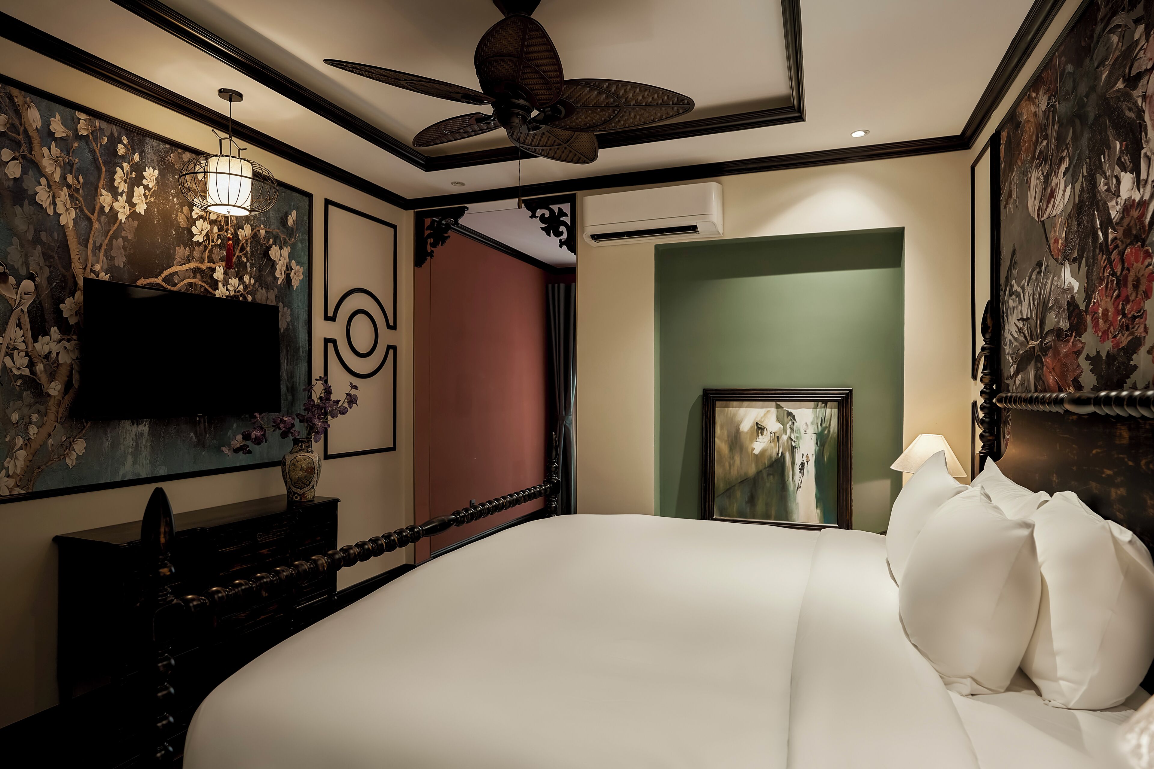 Quarto com cama grande, ventoinha no teto, televisão de tela plana e obras de arte nas paredes.