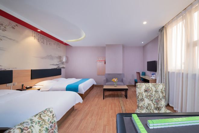 Quarto de hotel com duas camas, uma escrivaninha, uma cadeira e uma televisão.