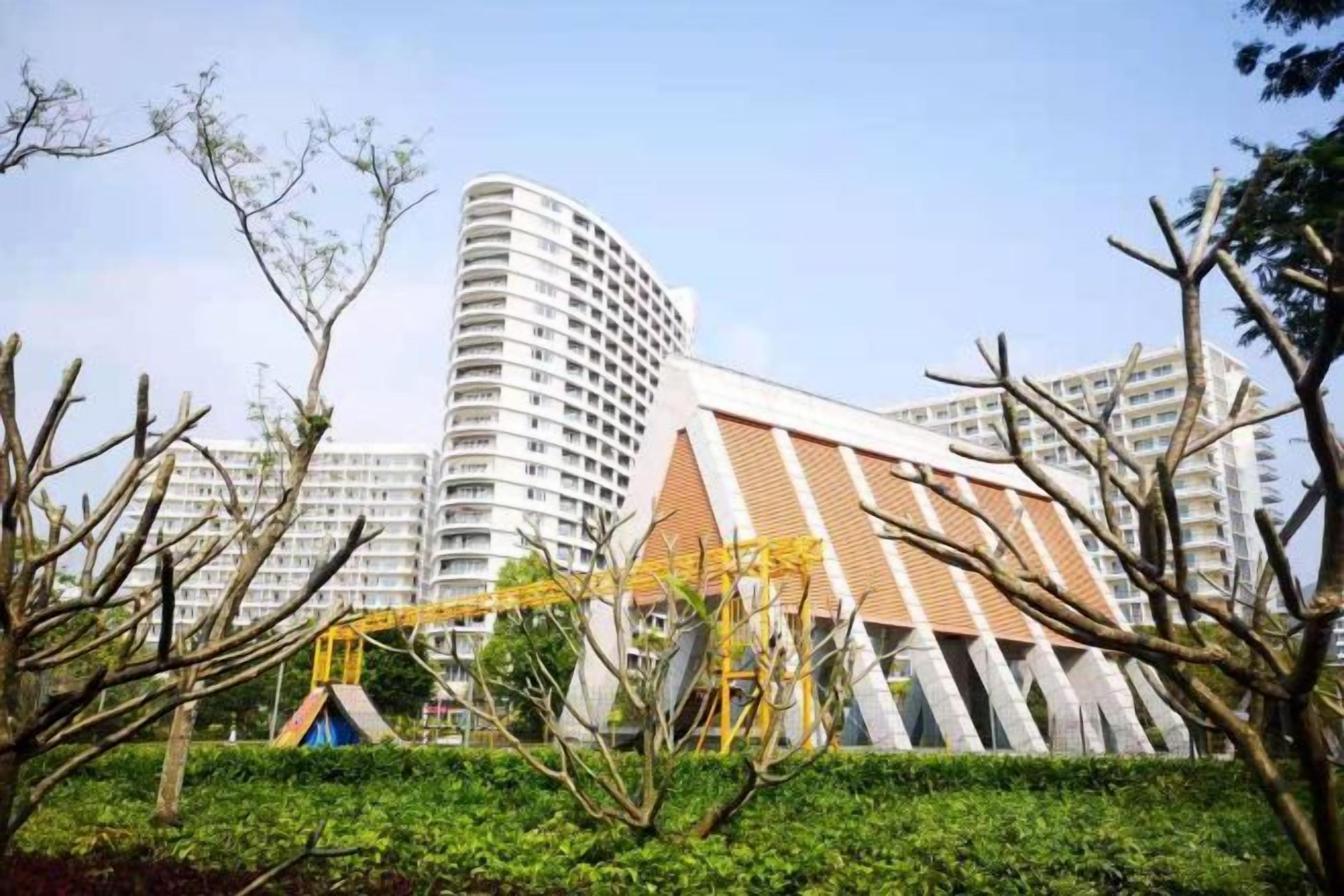 Um edifício moderno com um design arquitetônico singular, cercado por vegetação e árvores.