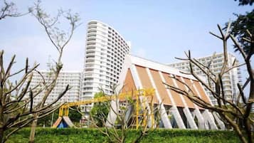 Um edifício moderno com um design arquitetônico singular, cercado por vegetação e árvores.
