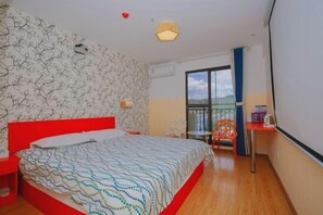 Quarto com cama vermelha, uma mesinha, uma cadeira e janela com vista.