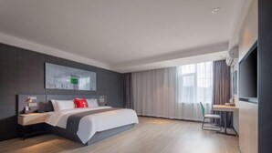 Quarto de hotel moderno com uma cama grande, uma mesa e uma televisão.