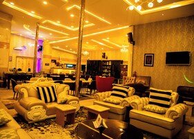 Um hall de hotel com design moderno, apresentando um bar, áreas de estar e um lustre.