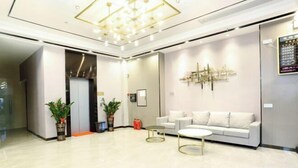 Um hall moderno com um sofá branco, uma mesa de centro redonda e um lustre decorativo.
