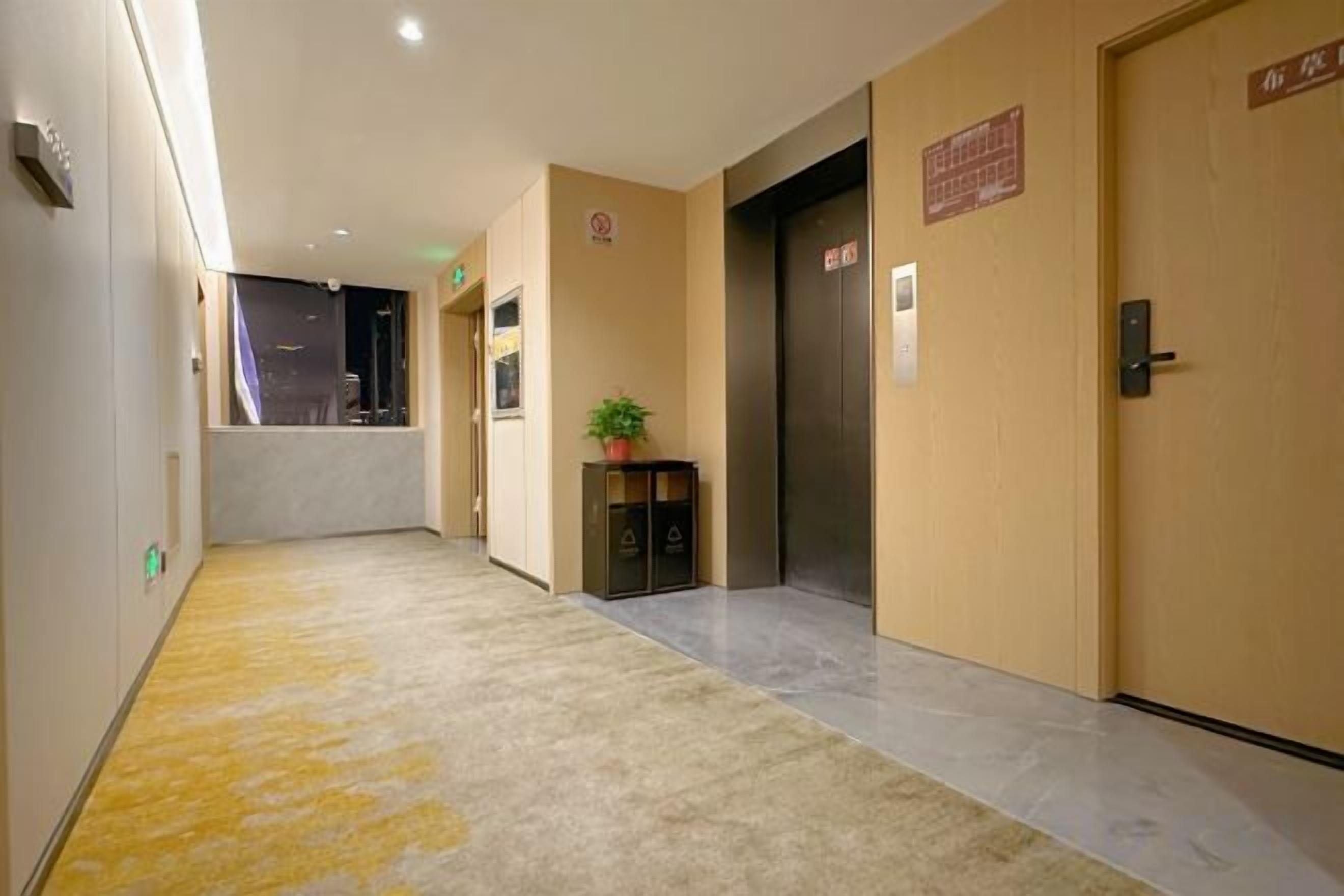 Corredor de hotel com piso carpetado, balcão de recepção e elevador.