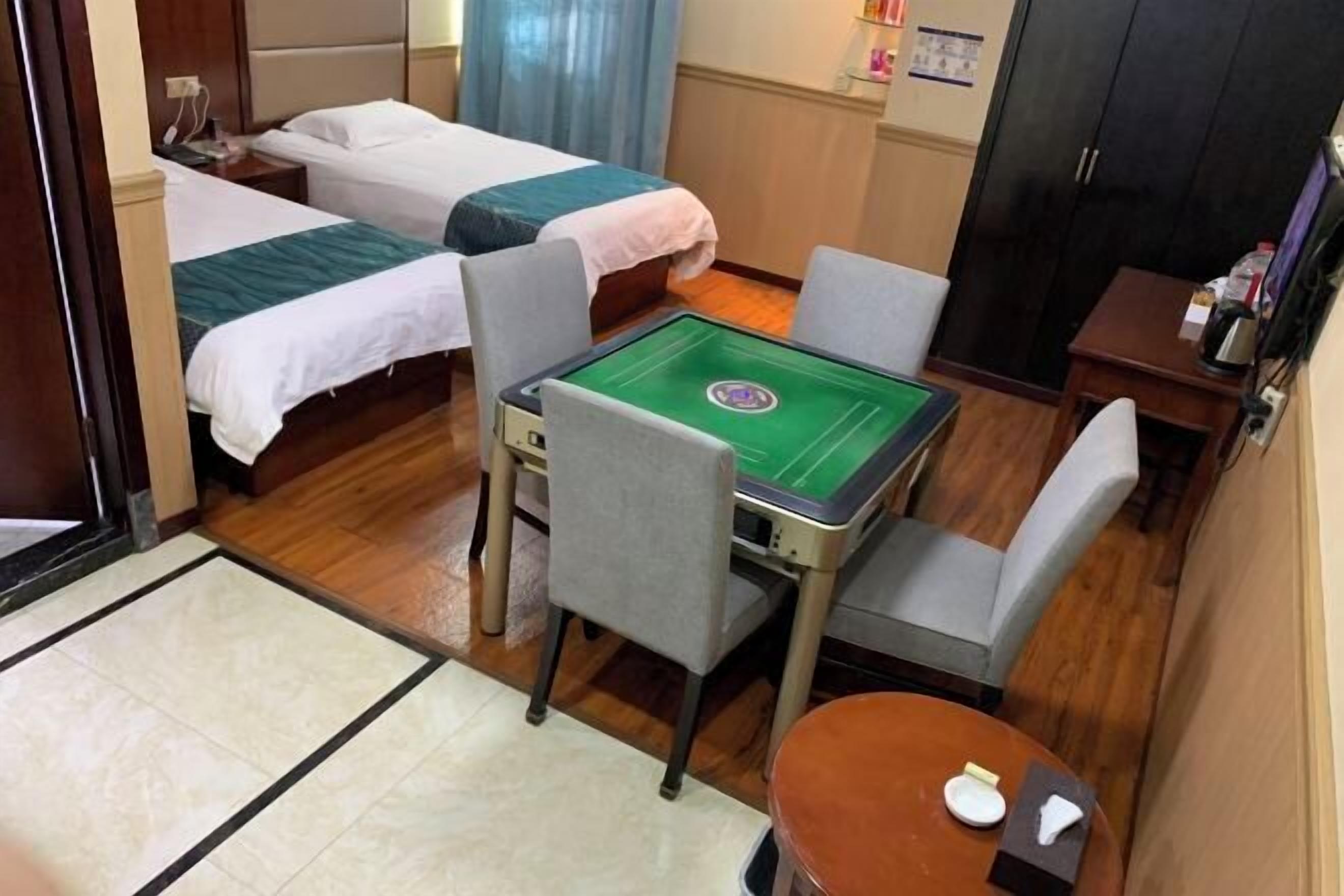 Quarto de hotel com duas camas, mesa de bilhar pequena e área de estar com cadeiras.