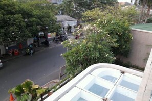 Vista da rua com um prédio em primeiro plano e árvores ao fundo.